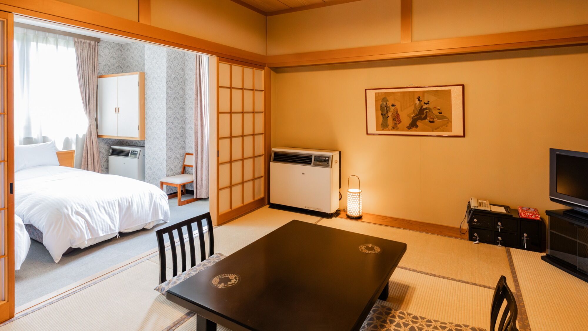 Quarto de hotel com cama, escrivaninha, cadeira, televisão, aquecedor e um quadro na parede.
