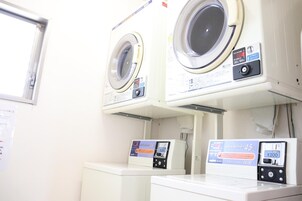 Uma lavanderia com duas máquinas de lavar roupa e uma secadora.