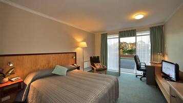 Quarto de hotel com cama, escrivaninha, cadeira, televisão, abajur e vista para o exterior.