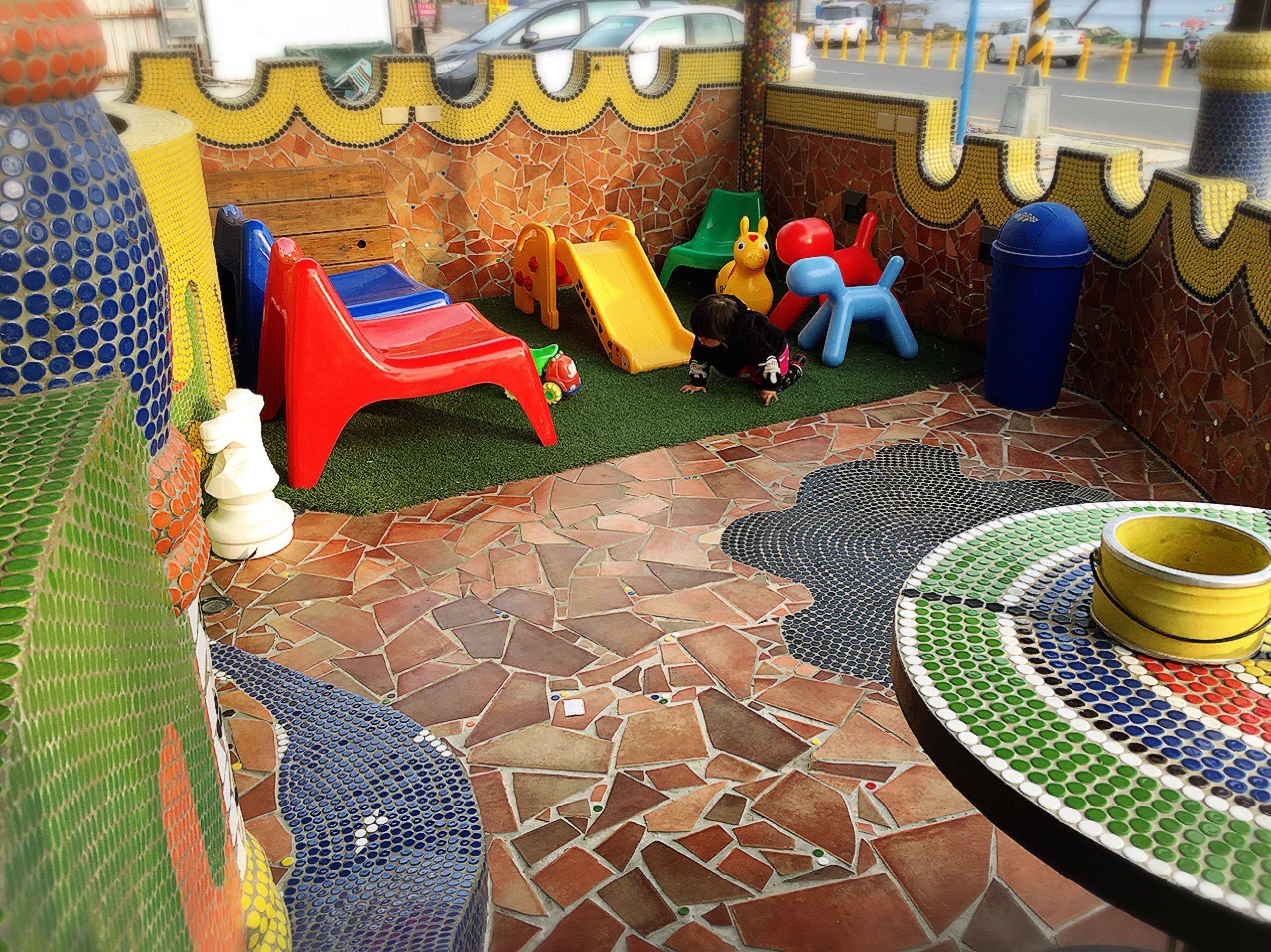 Uma área de recreação infantil com um escorrega, cadeiras pequenas e um cavalo de brinquedo.