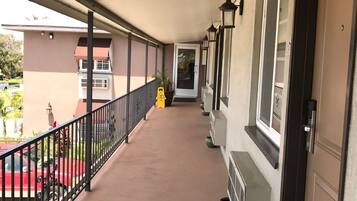 Varanda coberta com guarda-corpo de metal, porta e janela.