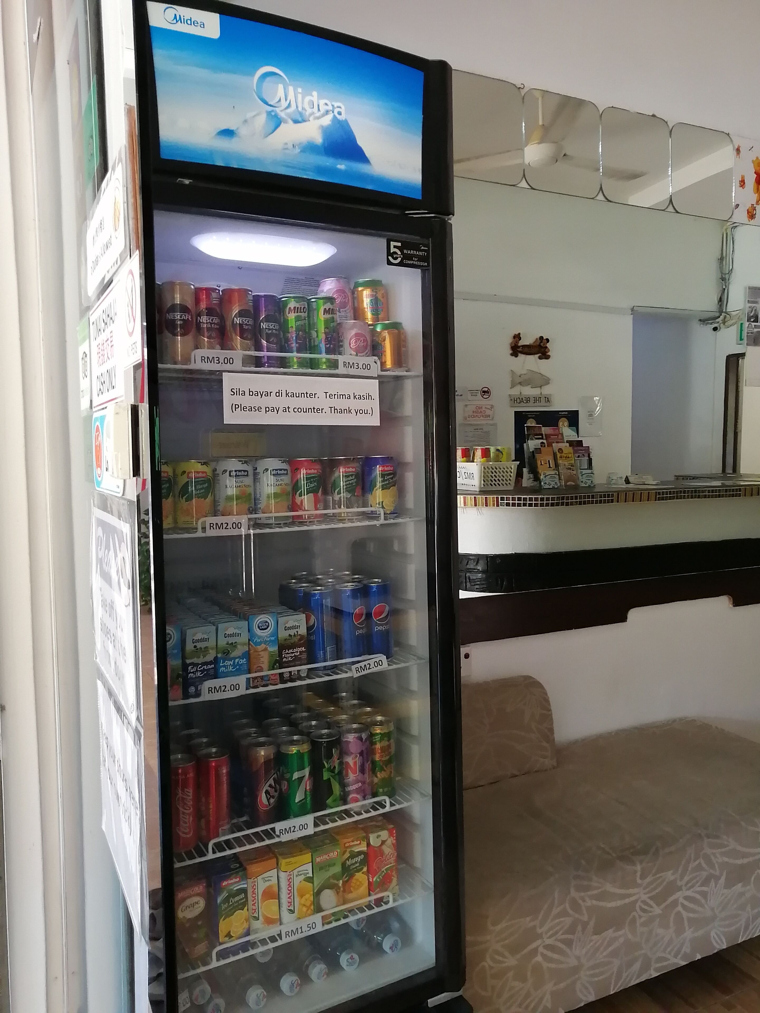 Máquina de vendas automática repleta de bebidas variadas, como refrigerantes e sumos, com etiquetas de preço visíveis.