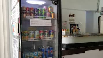 Máquina de vendas automática repleta de bebidas variadas, como refrigerantes e sumos, com etiquetas de preço visíveis.