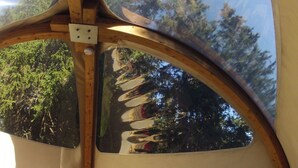 Quarto com cama, janela e vista para árvores.