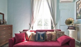 Quarto com sofá vermelho, cómoda de madeira, radiador e um gramofone.