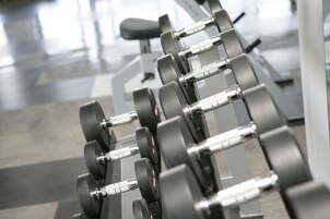 Uma fileira de halteres pretos em um suporte em uma academia.