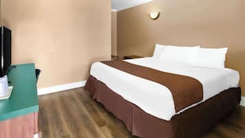 Quarto de hotel com uma cama, uma escrivaninha e uma televisão.
