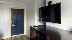 Quarto com porta azul escura, televisão de tela plana montada e painel de madeira para entretenimento.