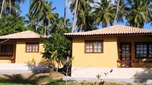 Dois edifícios amarelos com telhados de cerâmica, rodeados por palmeiras.