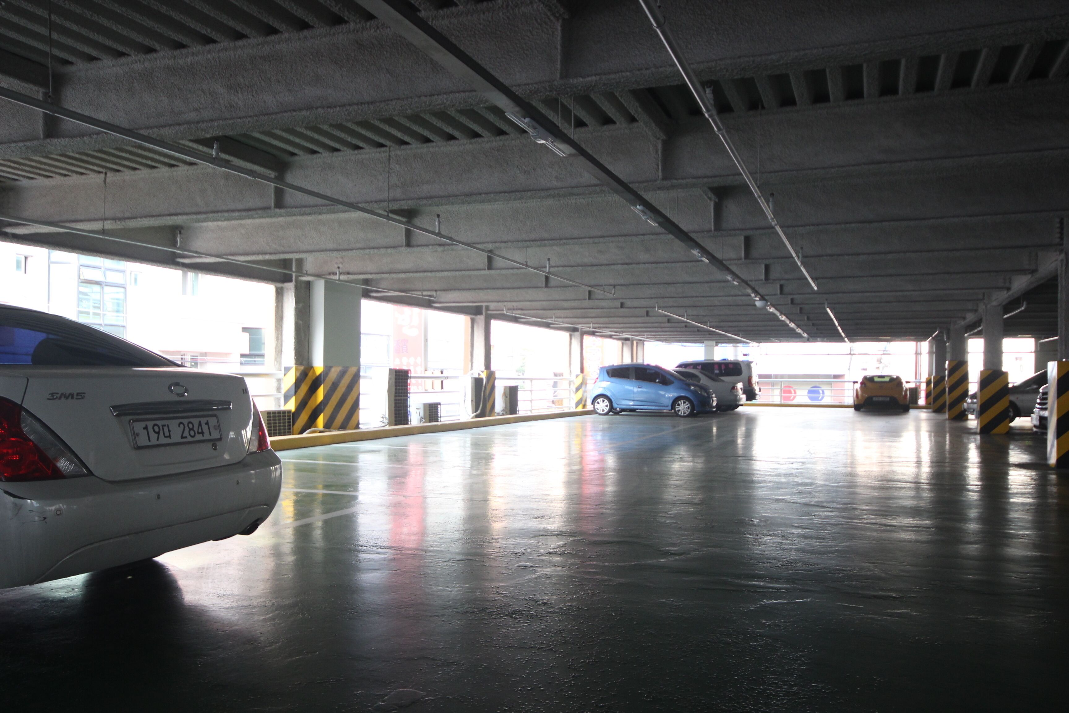 Garagem de estacionamento em vários níveis, com pisos e tetos de concreto, exibindo vários carros estacionados.