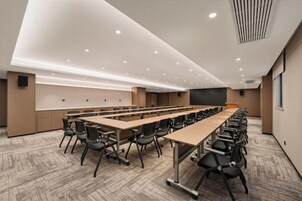 Uma sala de conferência com uma mesa comprida, cadeiras e um projetor.