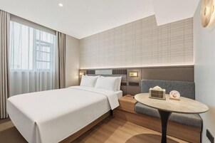Quarto de hotel com cama grande, uma mesinha e área de estar.