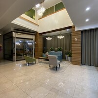 Um hall amplo com teto alto, um candelabro e área de estar com sofás e poltronas.