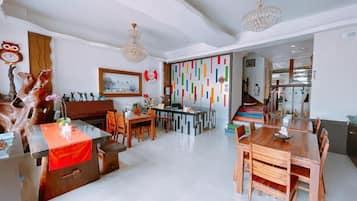 Uma sala de estar ampla com uma mesa de jantar, cadeiras, lareira e uma parede decorada com arte abstrata colorida.