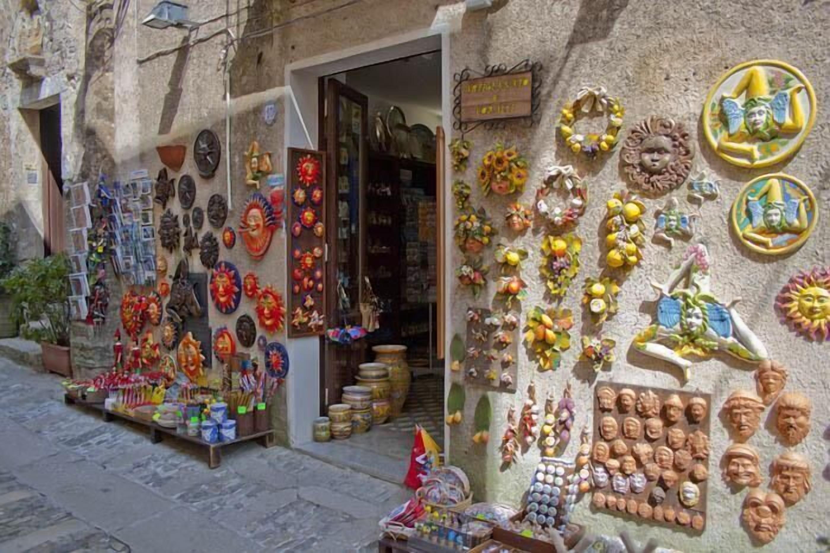 Uma rua estreita com lojas exibindo diversos itens como máscaras, esculturas e cerâmica.