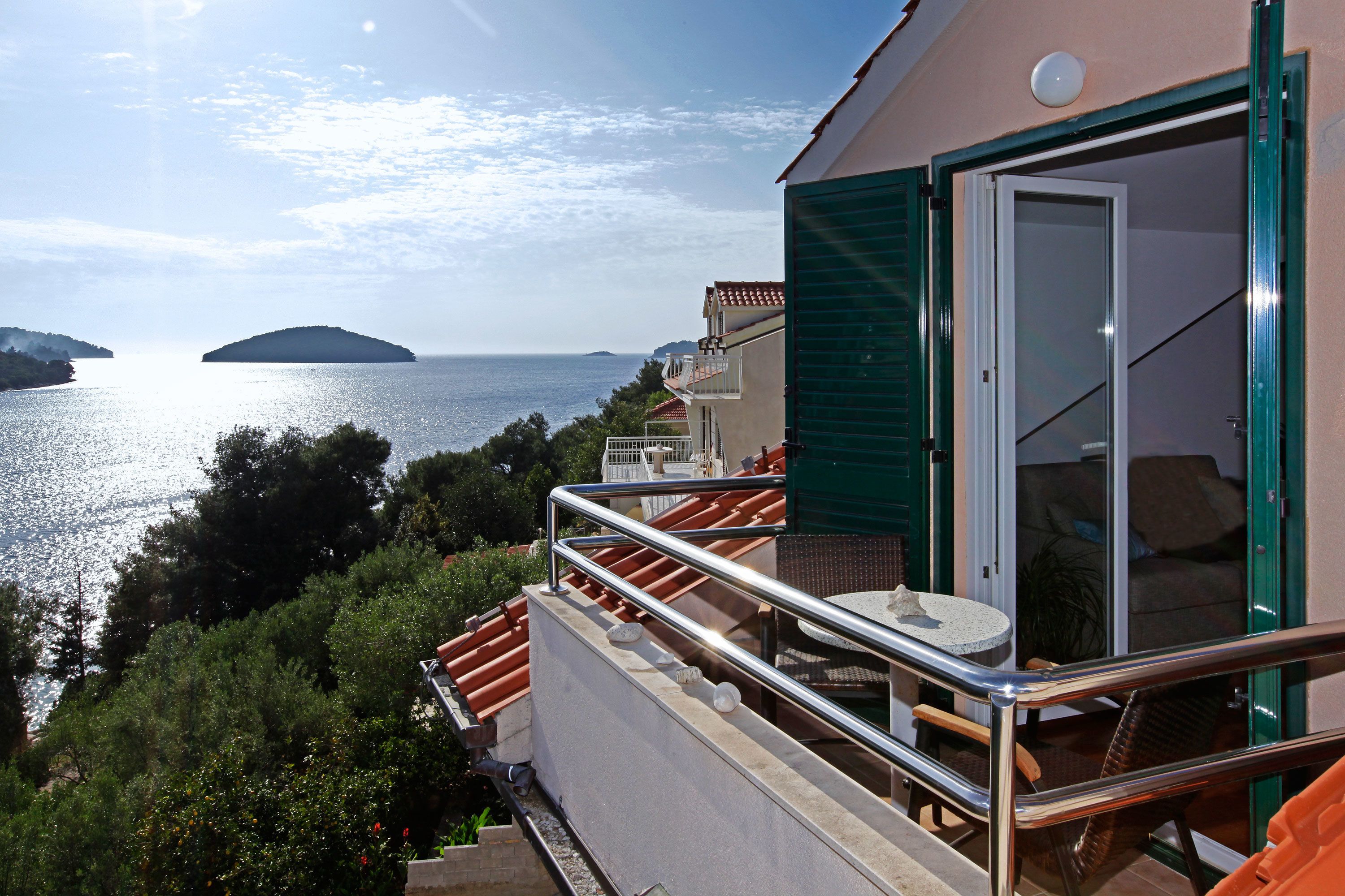 Uma varanda com vista para o mar, uma mesa e uma cadeira.