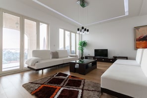 Uma sala de estar moderna com sofá, mesa de centro, televisão e uma planta.