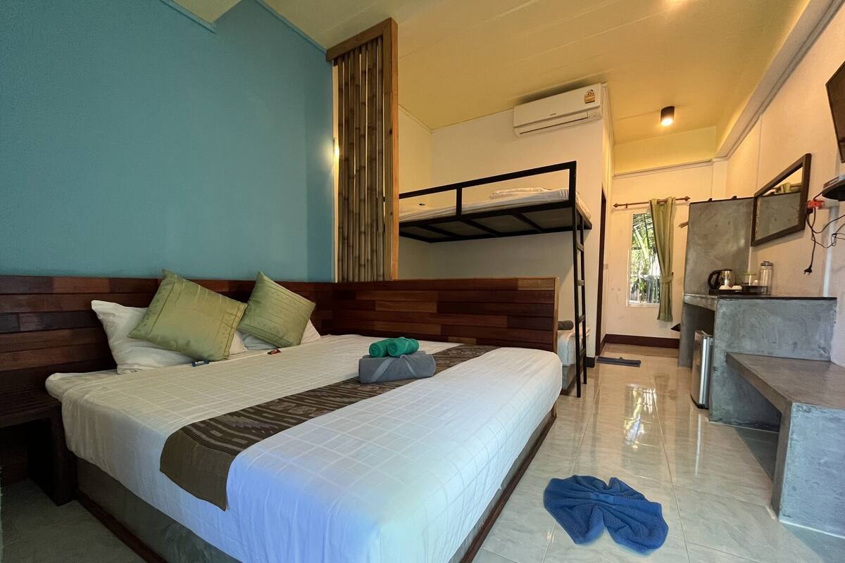 Quarto de hotel com beliche, escrivaninha e banheiro.