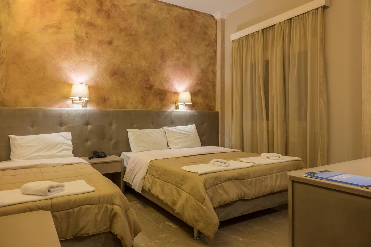 Quarto de hotel com duas camas, uma escrivaninha e um minibar.