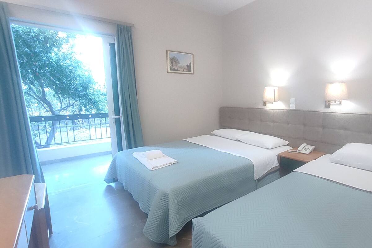 Quarto de hotel com duas camas, varanda e um quadro na parede.