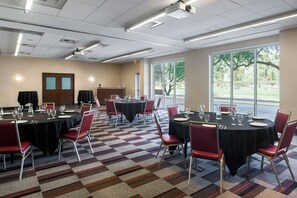 Uma sala de conferência com várias mesas, cadeiras e um projetor no teto.