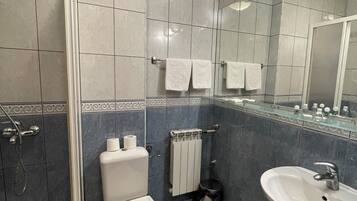 Casa de banho com chuveiro, sanita, bidé e lavatório.