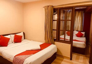 Quarto de hotel com uma cama grande, uma cama menor e uma janela com cortinas.
