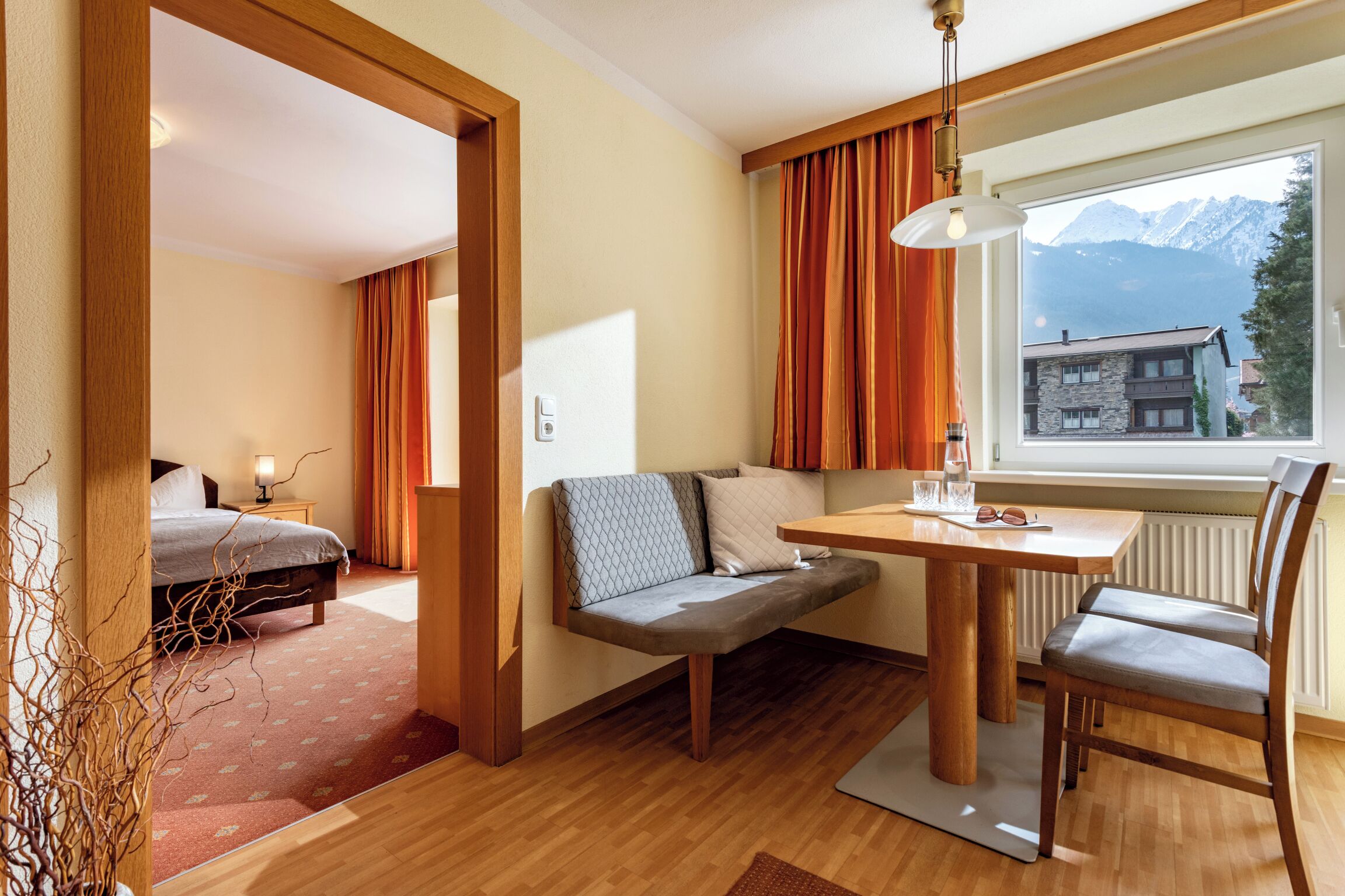 Quarto com cama, sofá, mesa de jantar e vista para as montanhas.