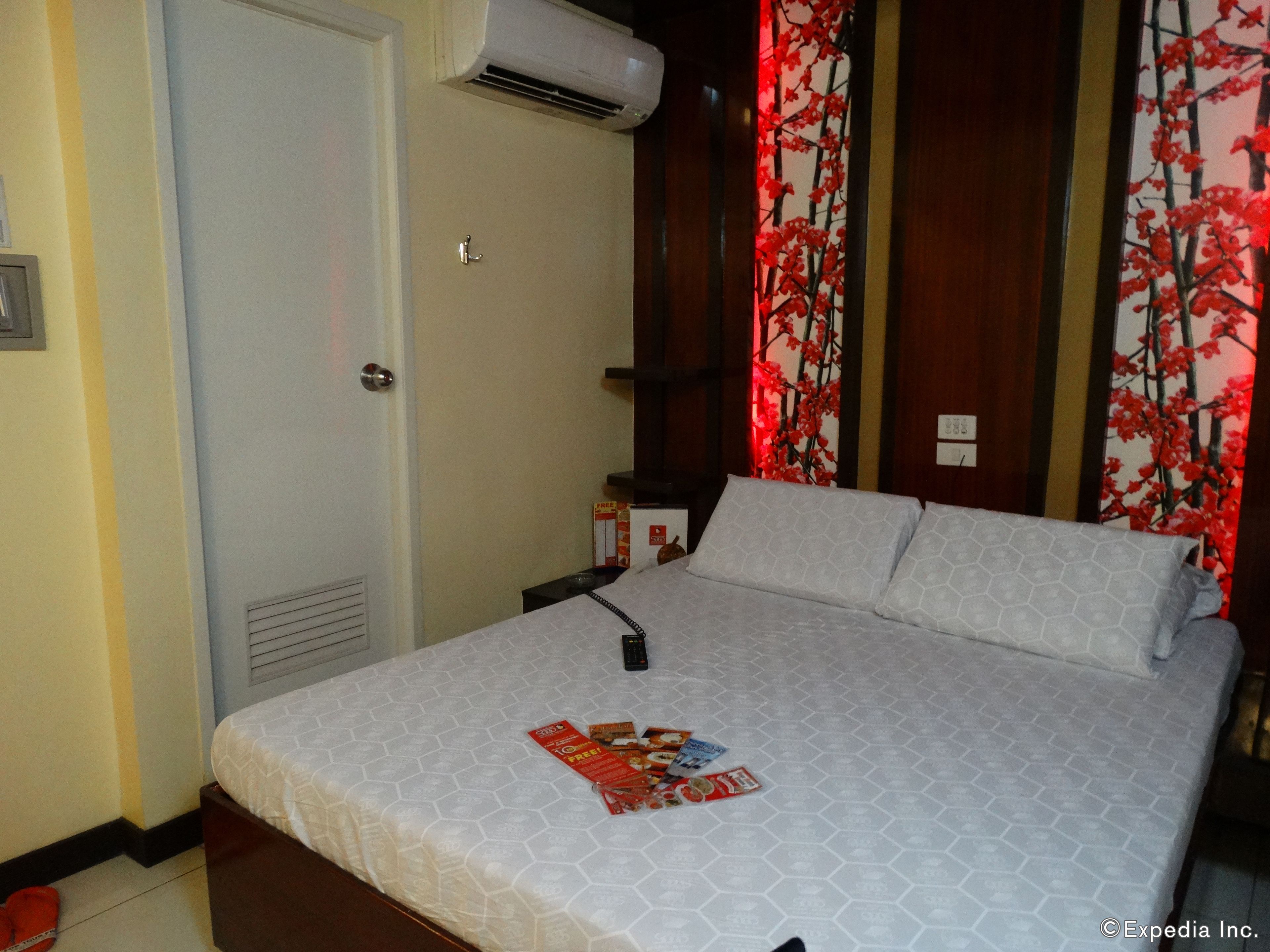 Quarto de hotel com cama, mesa de cabeceira, ar condicionado fixado na parede e porta.