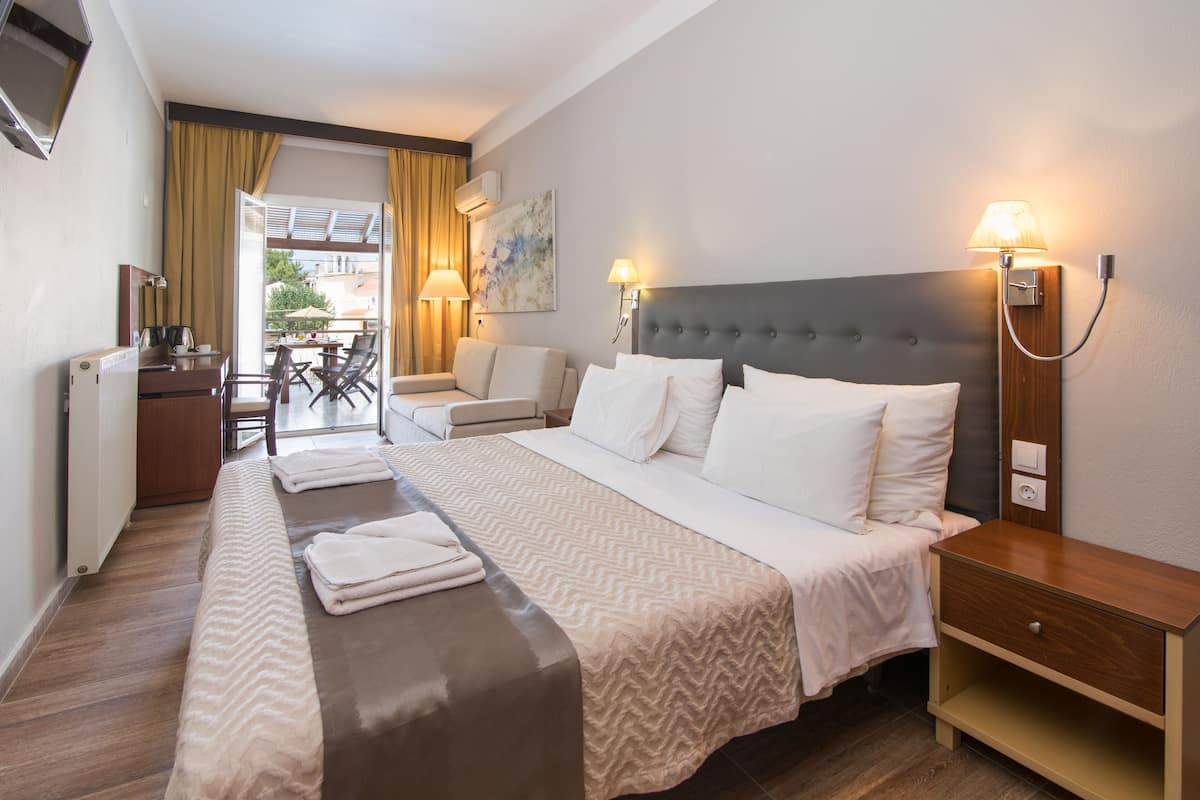 Quarto de hotel com uma cama grande, mesas de cabeceira, uma escrivaninha e uma cadeira.