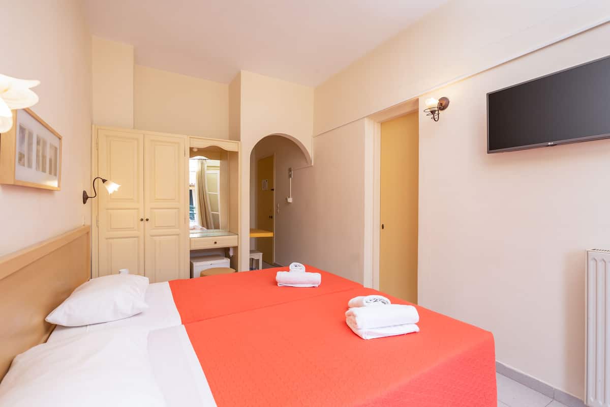 Quarto de hotel com cama, televisão e guarda-roupa.
