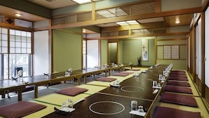 Uma sala de conferência com mesas compridas, tatames e decoração japonesa tradicional.