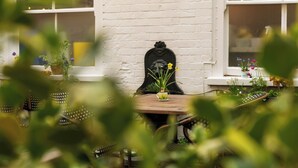 Uma parede de tijolos brancos, uma janela e uma mesa com uma planta em vaso.