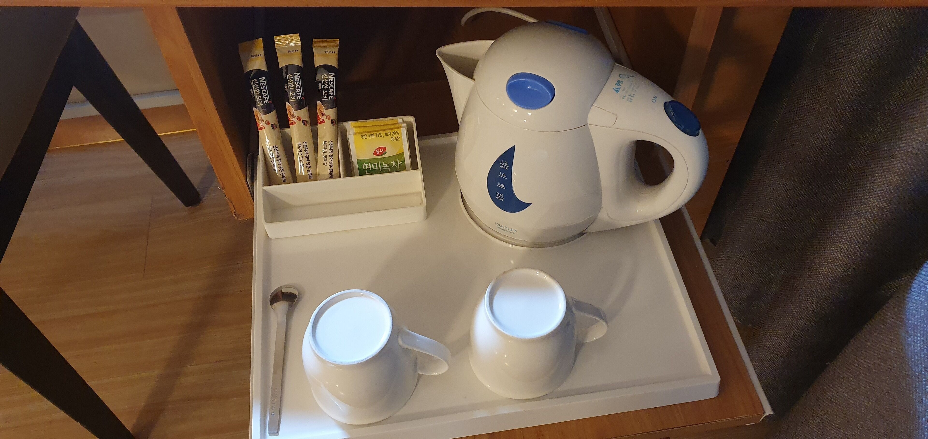 Uma bandeja com uma cafeteira, duas chávenas, uma colher e três saquinhos de café.