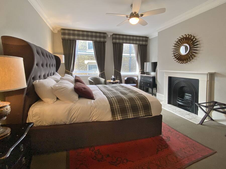 Quarto com cama, luminária, lareira e ventilador de teto.