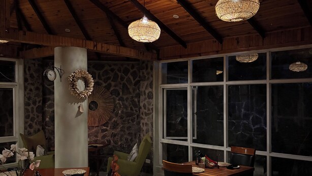Uma sala de jantar com teto de madeira, paredes de pedra e grandes janelas.