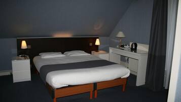 Quarto de hotel padrão com uma cama de solteiro, mesas de cabeceira, uma escrivaninha e uma cadeira.