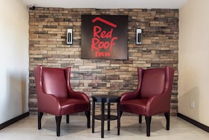 Lobby do Red Roof Inn com parede de pedra, duas poltronas de couro e uma mesa pequena.