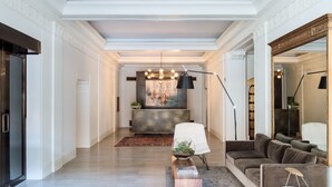 Uma sala de estar ampla com um sofá moderno, uma mesa de centro de vidro e um espelho grande.
