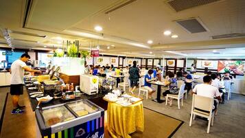 Restaurante estilo buffet com várias estações de comida e mesas.