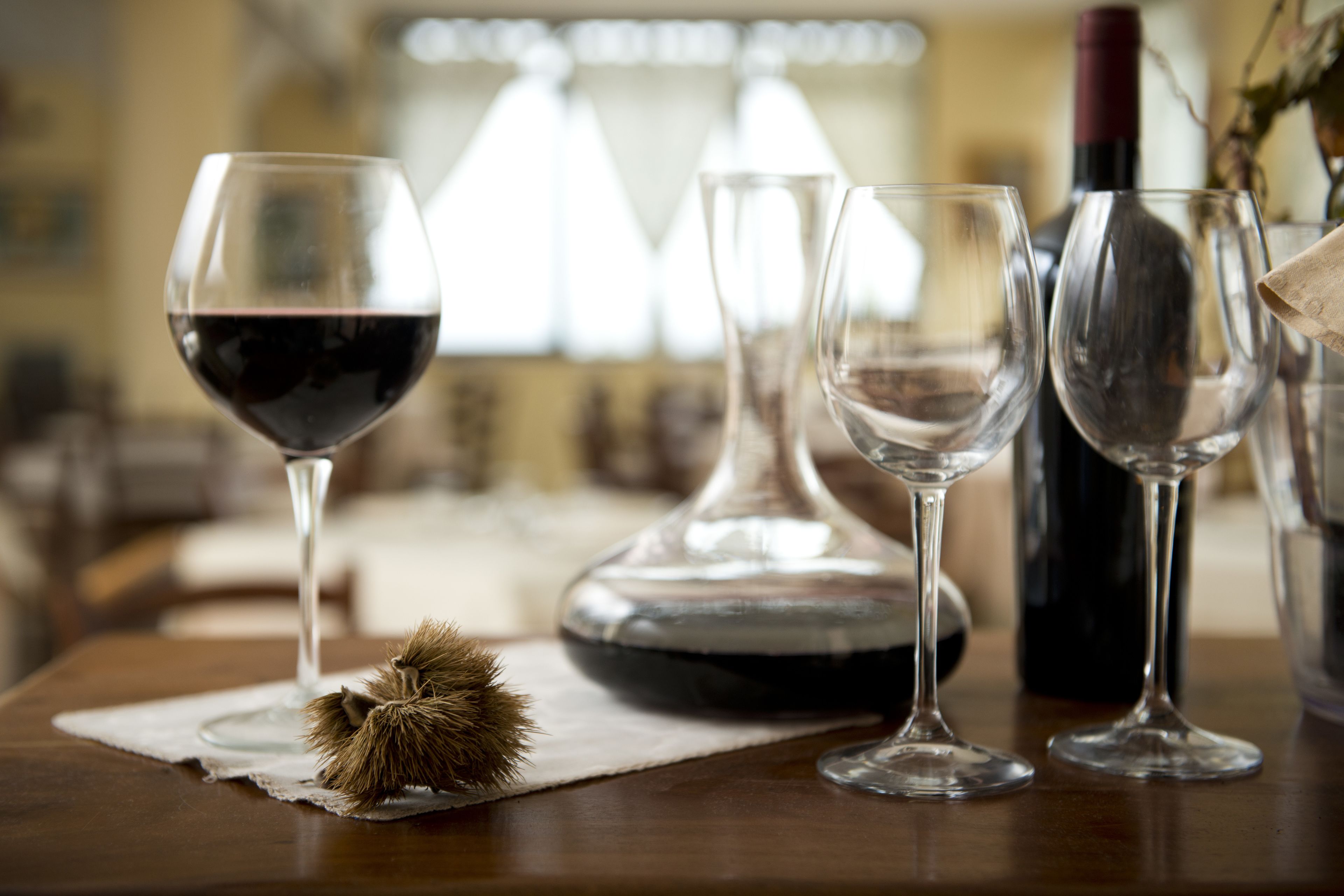 Uma mesa com copos de vinho e uma garrafa, uma escova de pele e um castiçal.