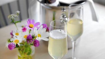 Uma taça de champanhe, uma garrafa de champanhe e um arranjo de flores sobre uma mesa.