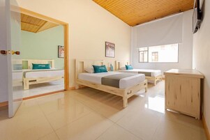 Quarto de hotel com duas camas, um armário de madeira e uma janela grande.