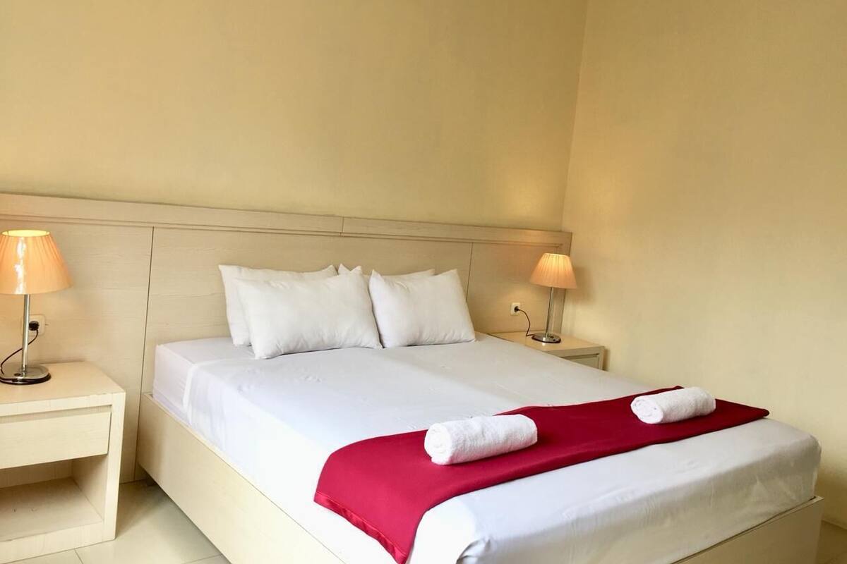 Quarto de hotel com uma cama, duas mesas de cabeceira e luminárias.