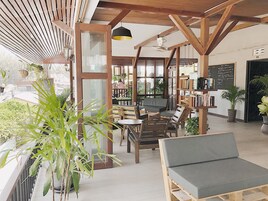 Um café acolhedor com mobiliário de madeira, um sofá verde e uma estante cheia de livros.
