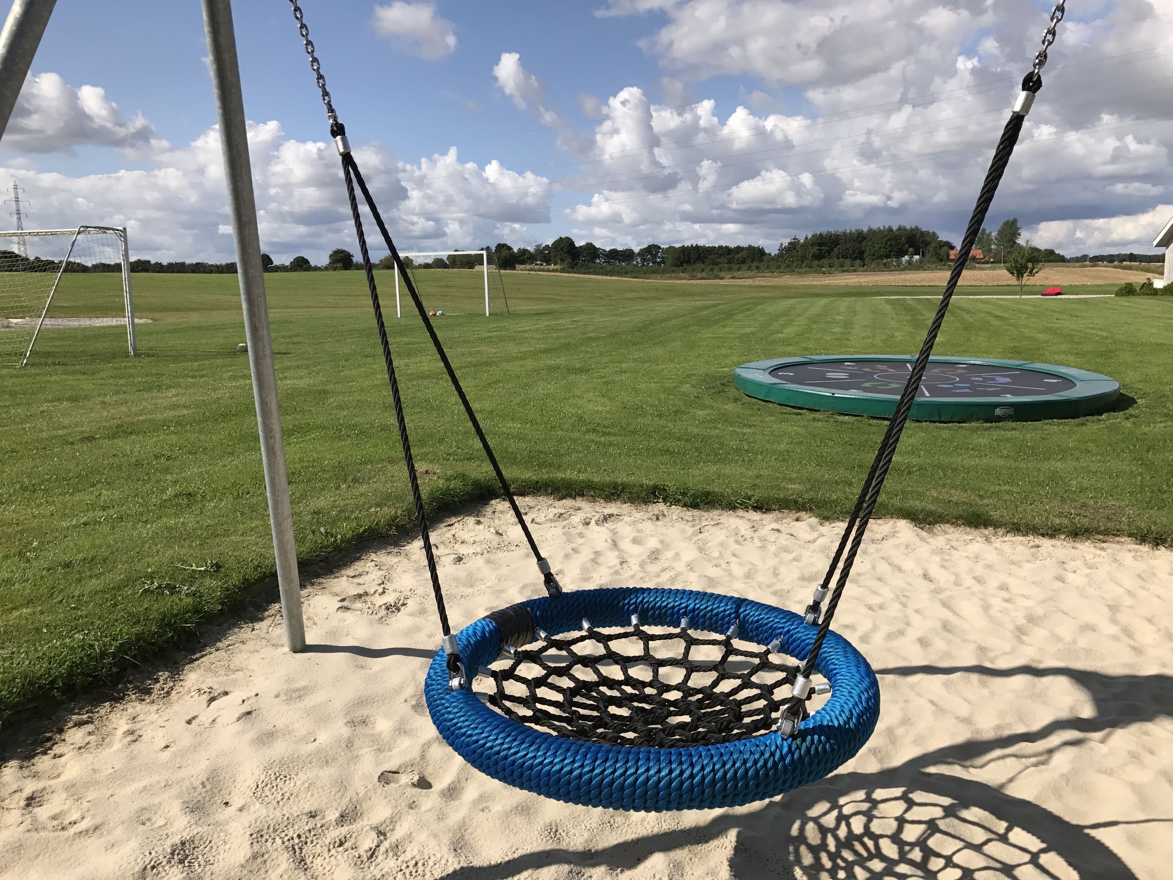 Um conjunto de baloiços com um baloiço de pneu azul num parque.