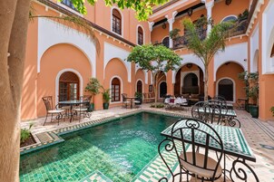 Um pátio com piscina, área de estar externa e arcos.