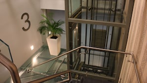 Um interior moderno com guarda-corpo de vidro, uma planta em vaso e o número 3 grande na parede.