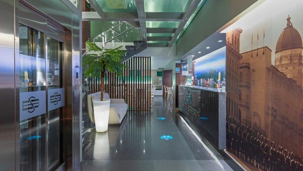 Um saguão moderno de hotel com balcão de recepção, área de estar e escada.