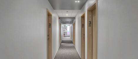 Corredor longo e estreito de hotel, com portas numeradas 3, 22 e 23.